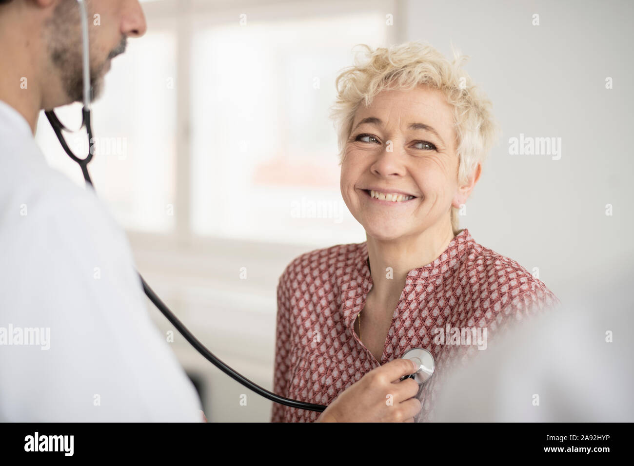 Doctor with stethoscope examining patient Stock Photo - Alamy