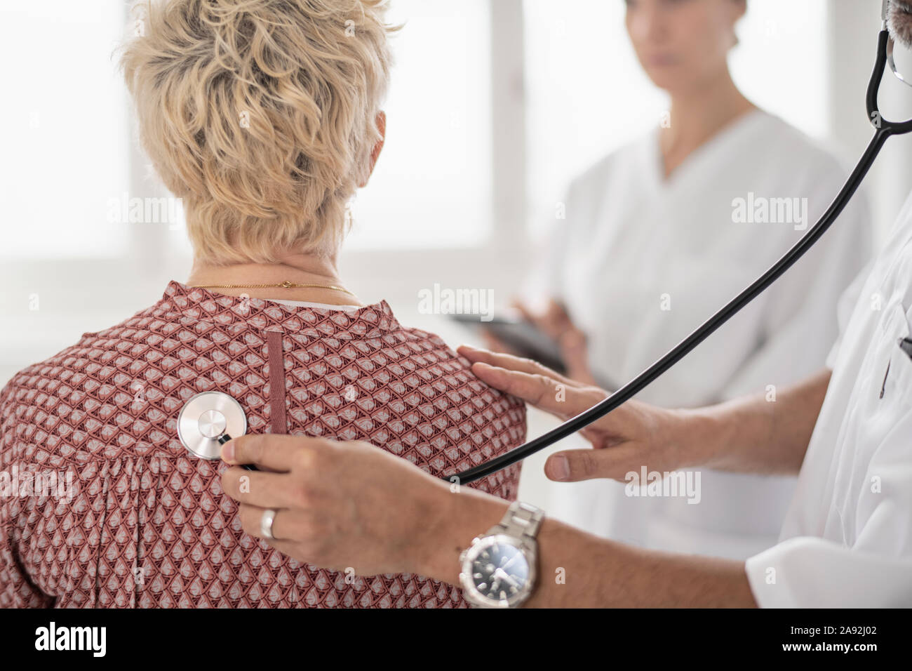Doctor with stethoscope examining patient Stock Photo - Alamy