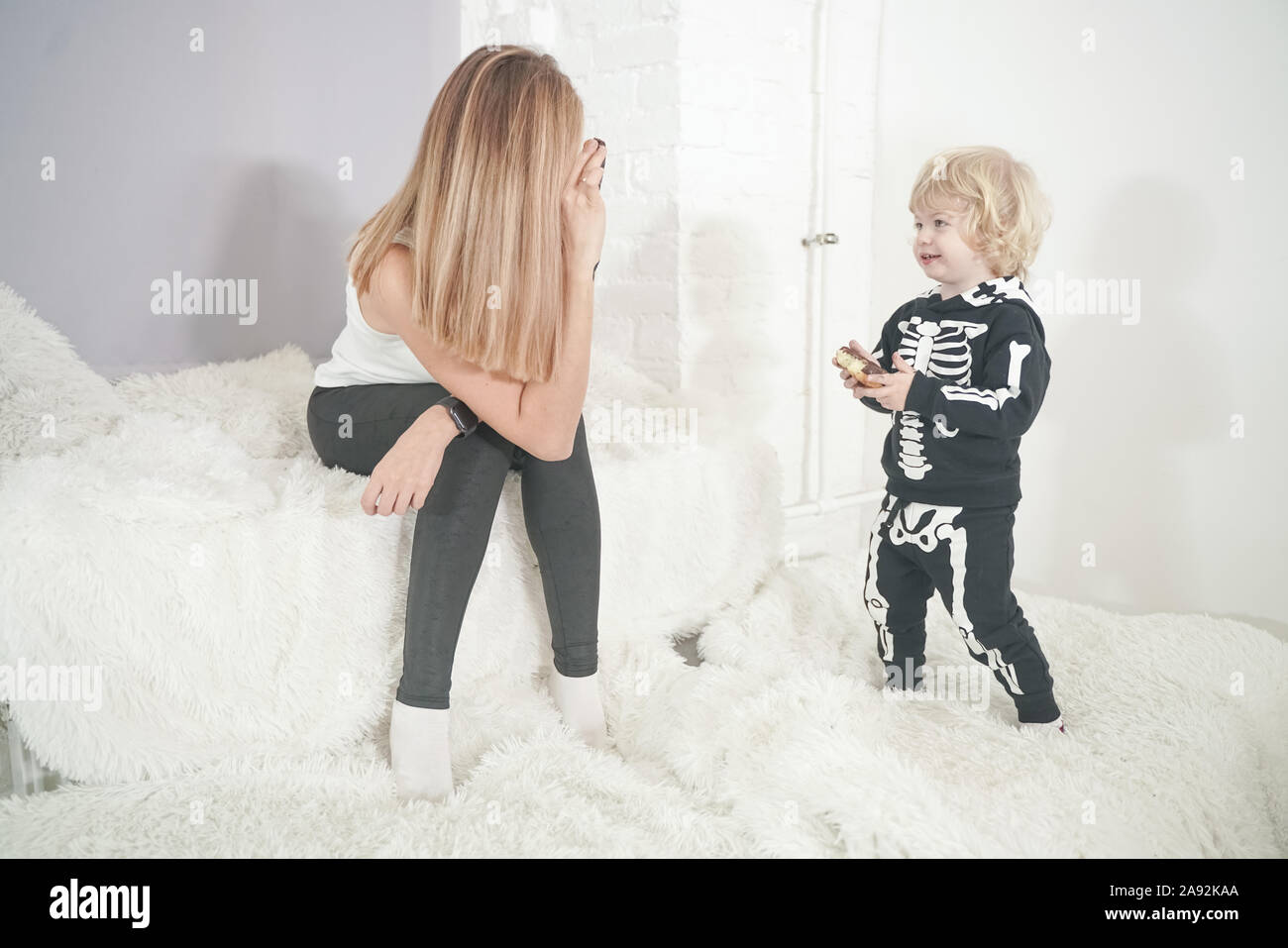 Mother and son child having fun with tasty sweet donuts indoors. Boy in ...