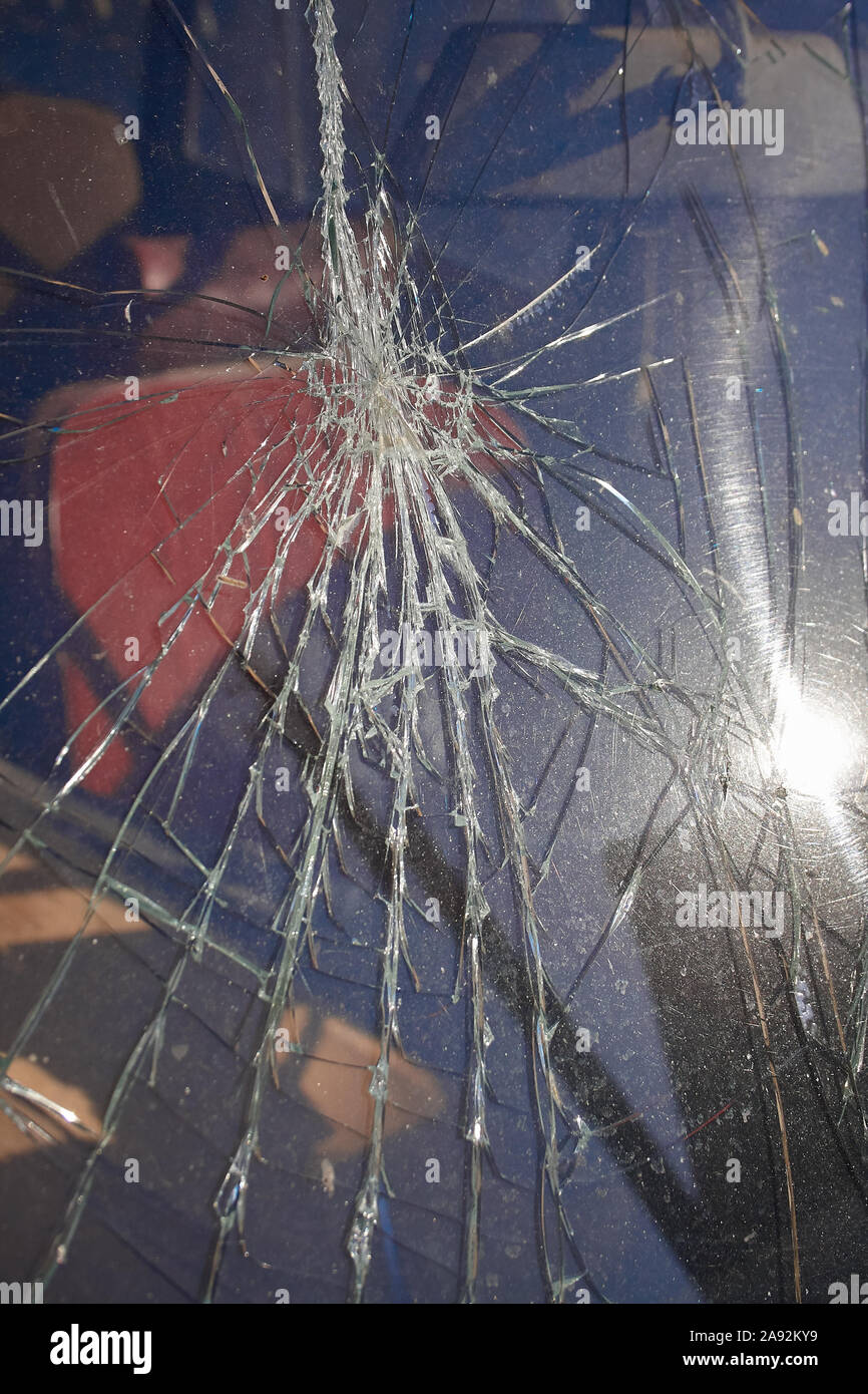 Cracks and glass shards radiate from the point of impact in a window ...