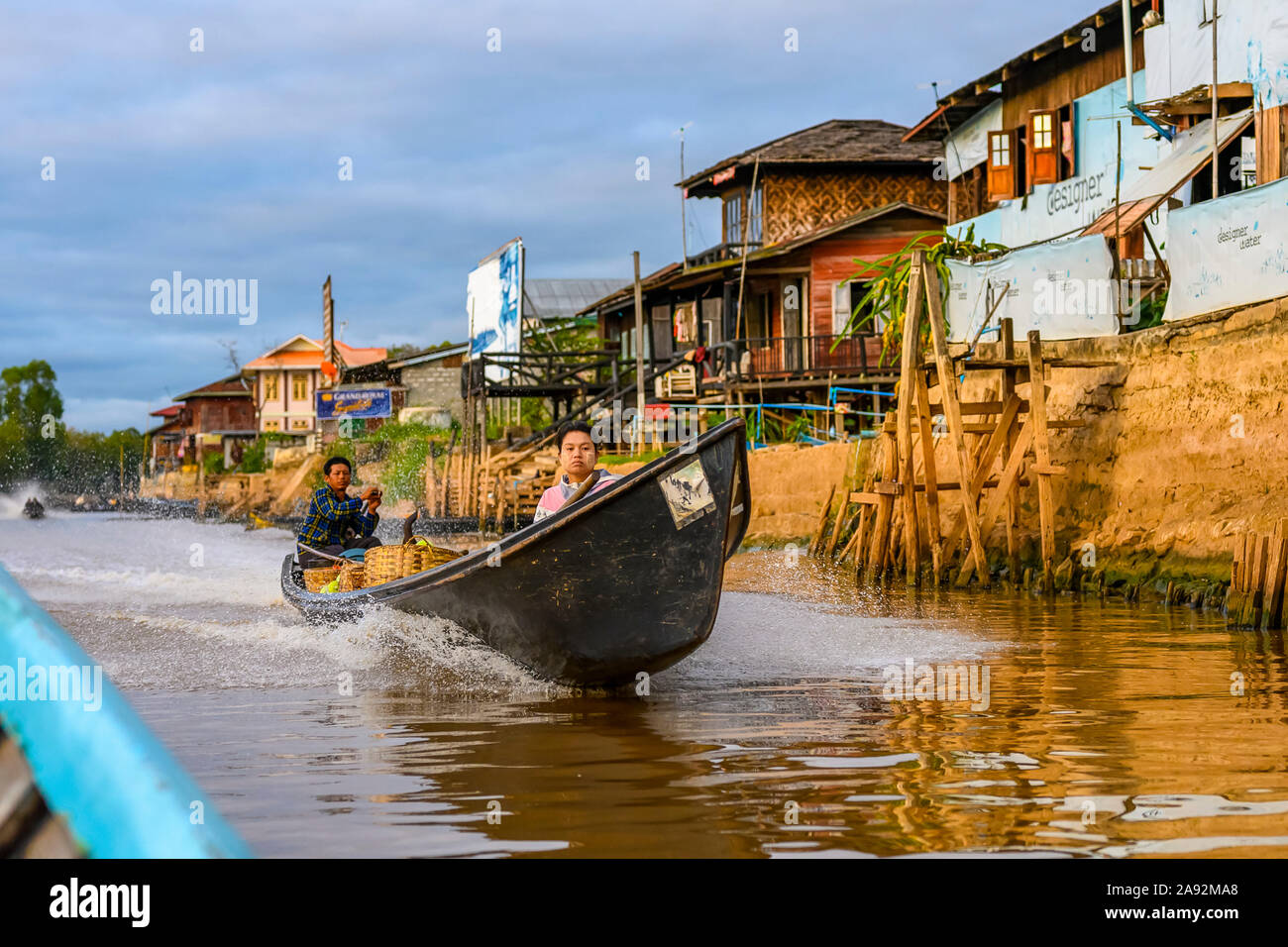 Boat with two passengers in the river along the shoreline; Yawngshwe ...