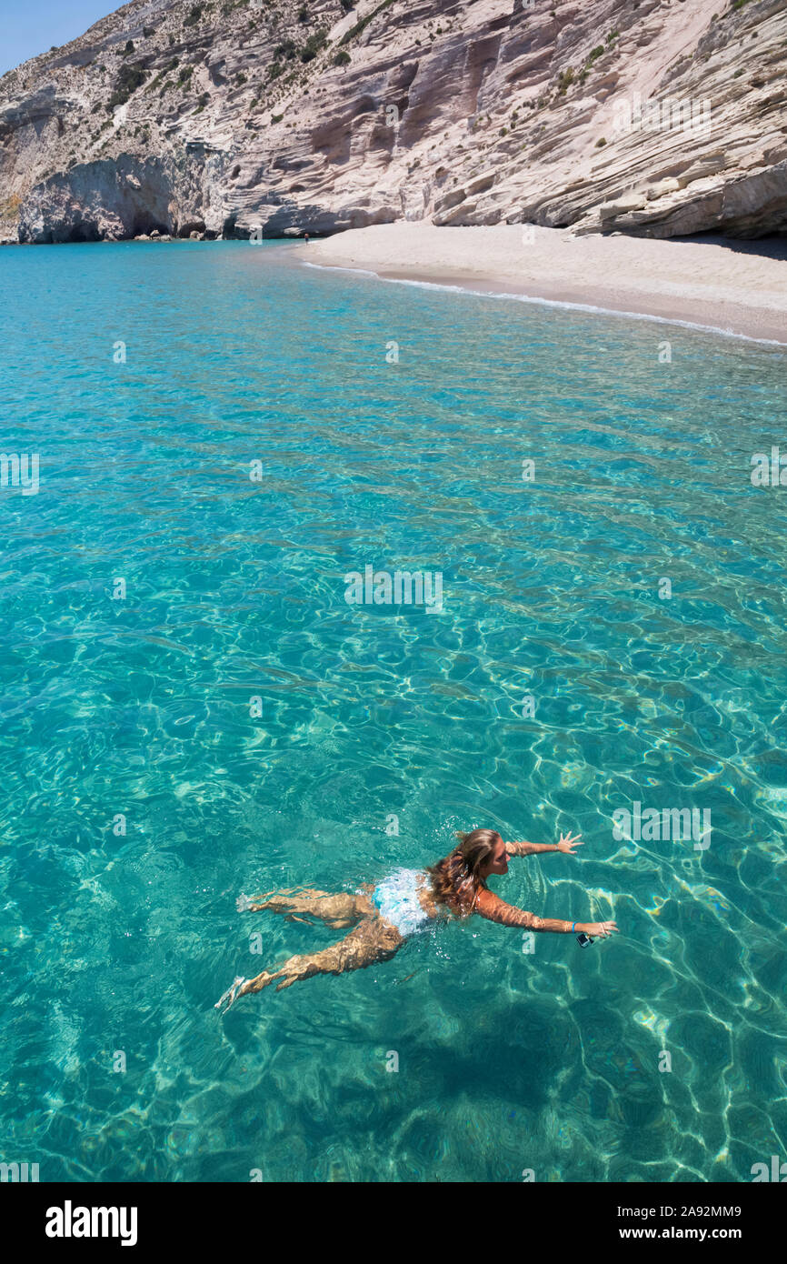Female tourist swimming in the clear, turquoise water of Galazia Nera ...