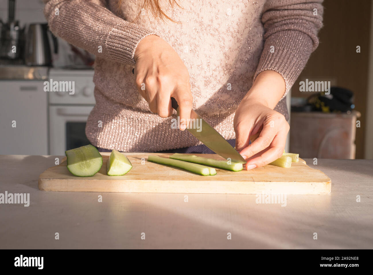 Woman cutting cucumber in kitchen Stock Photo - Alamy