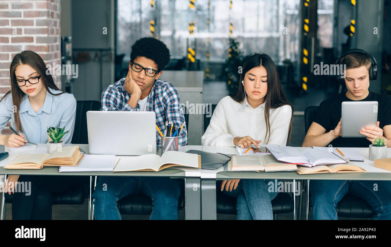 Diverse students studying in university library with gadgets Stock ...
