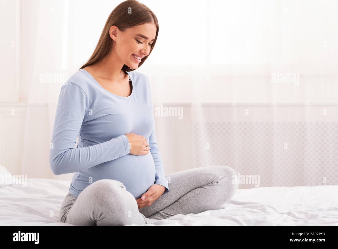 Expectant Girl Touching Belly Smiling Sitting On Bed In Bedroom Stock ...