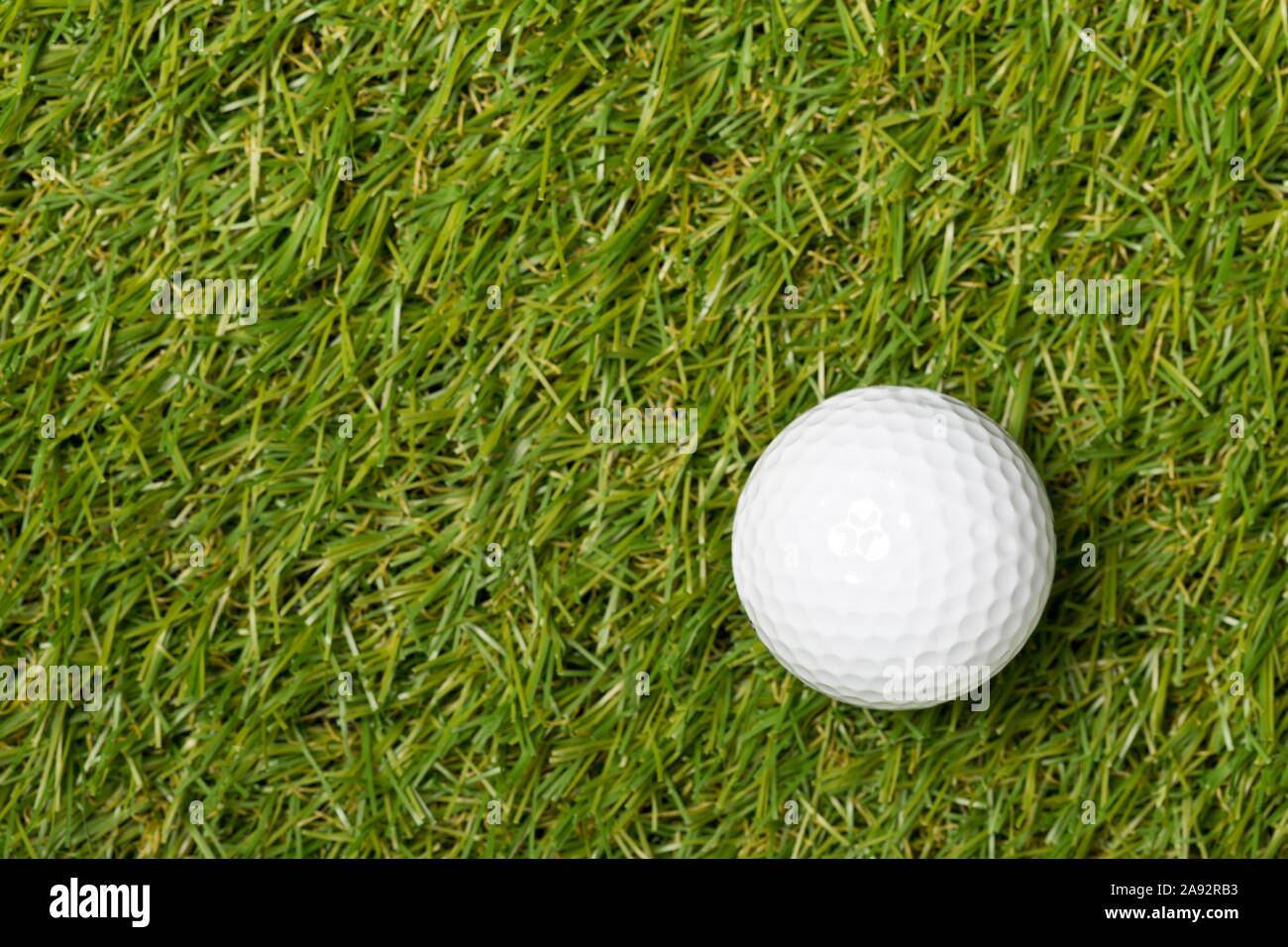 White golf ball on green grass lawn with copy space top view flat lay ...