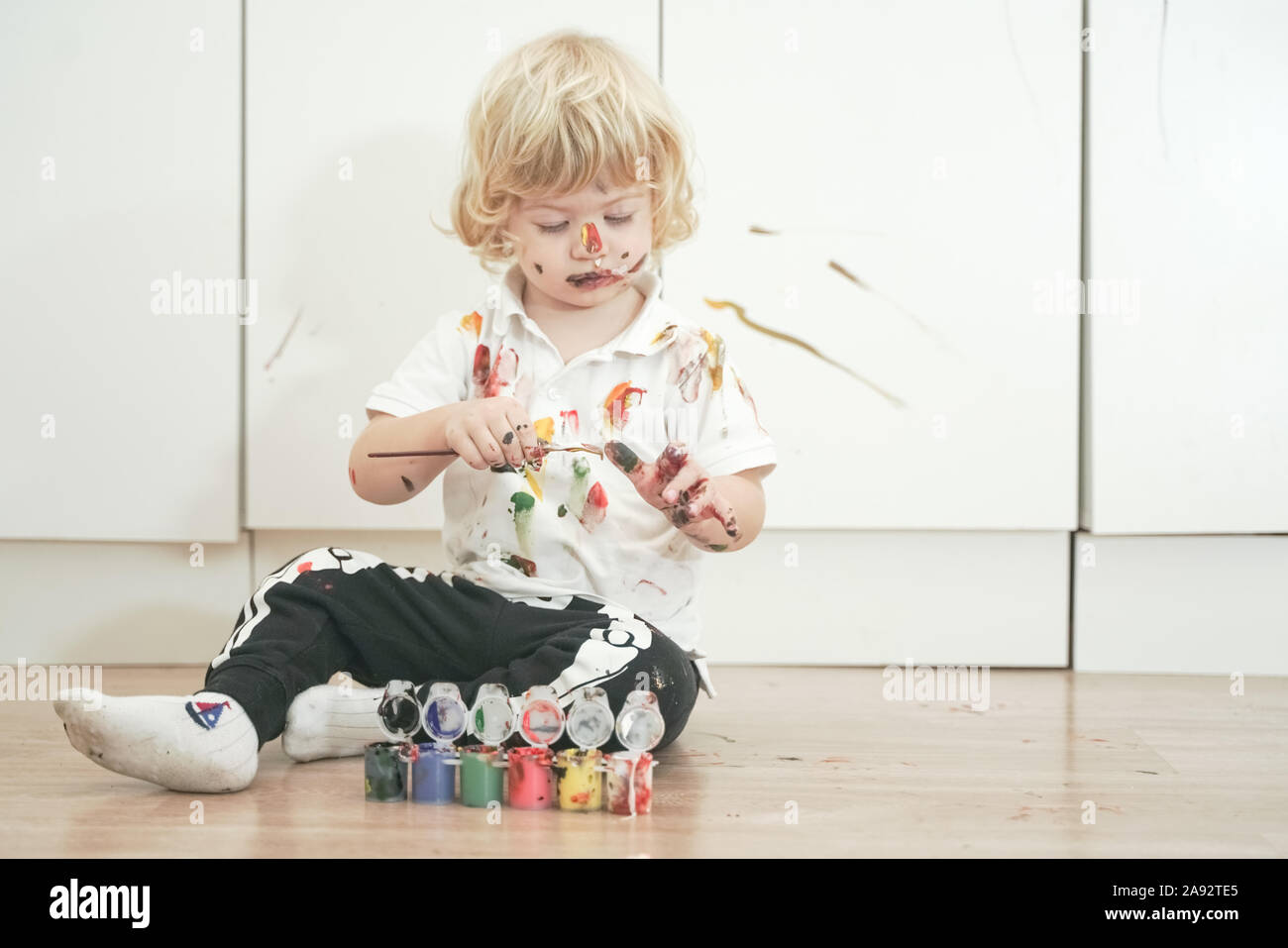two year old boy with hands and face painted in colorful paints ready ...