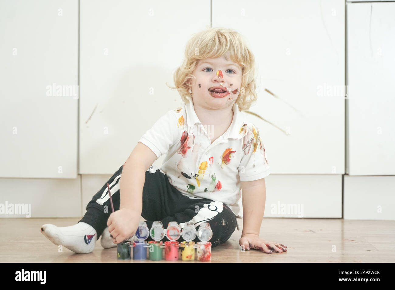 two year old boy with hands and face painted in colorful paints ready ...