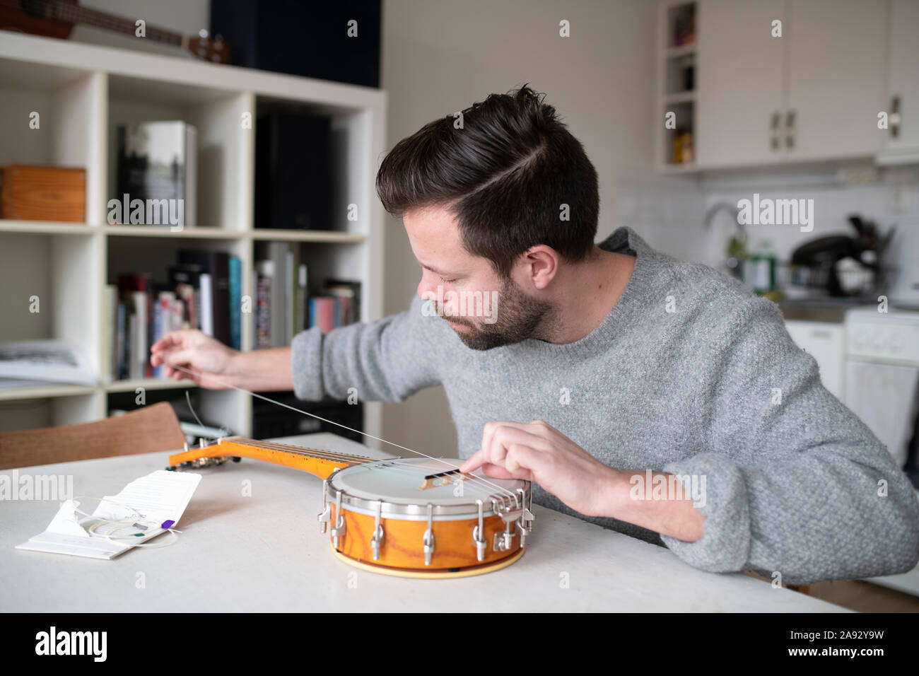 Man putting string on Stock Photo - Alamy