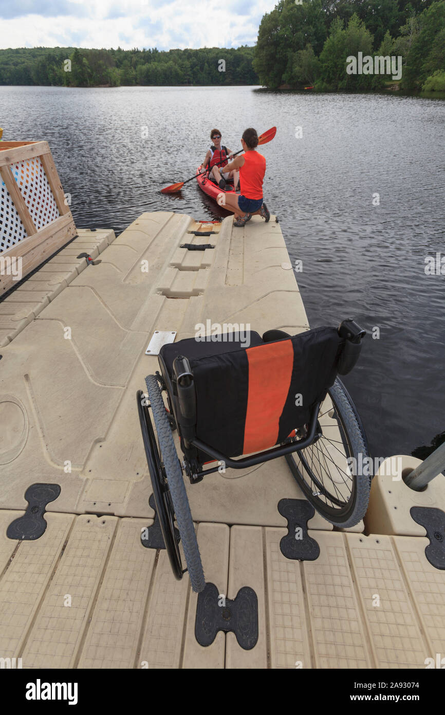 Instructor helping a woman with a Spinal Cord Injury with using a kayak ...