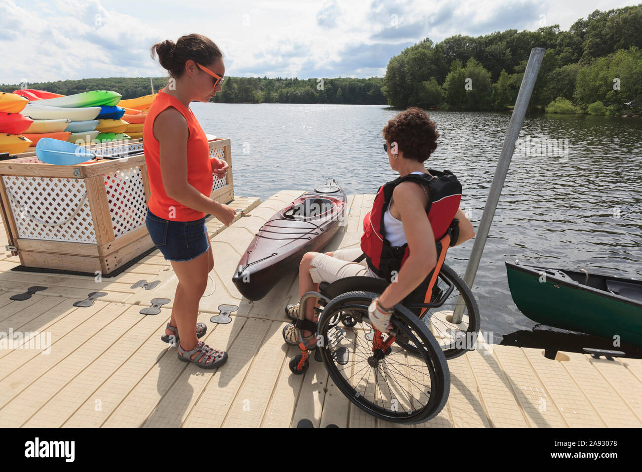 Instructor helping a woman with a Spinal Cord Injury with using a kayak ...
