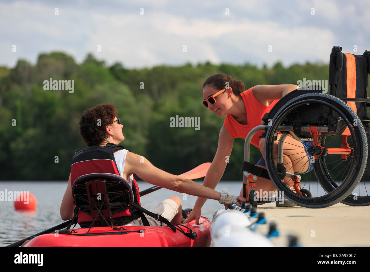 Instructor helping a woman with a Spinal Cord Injury use a kayak Stock ...