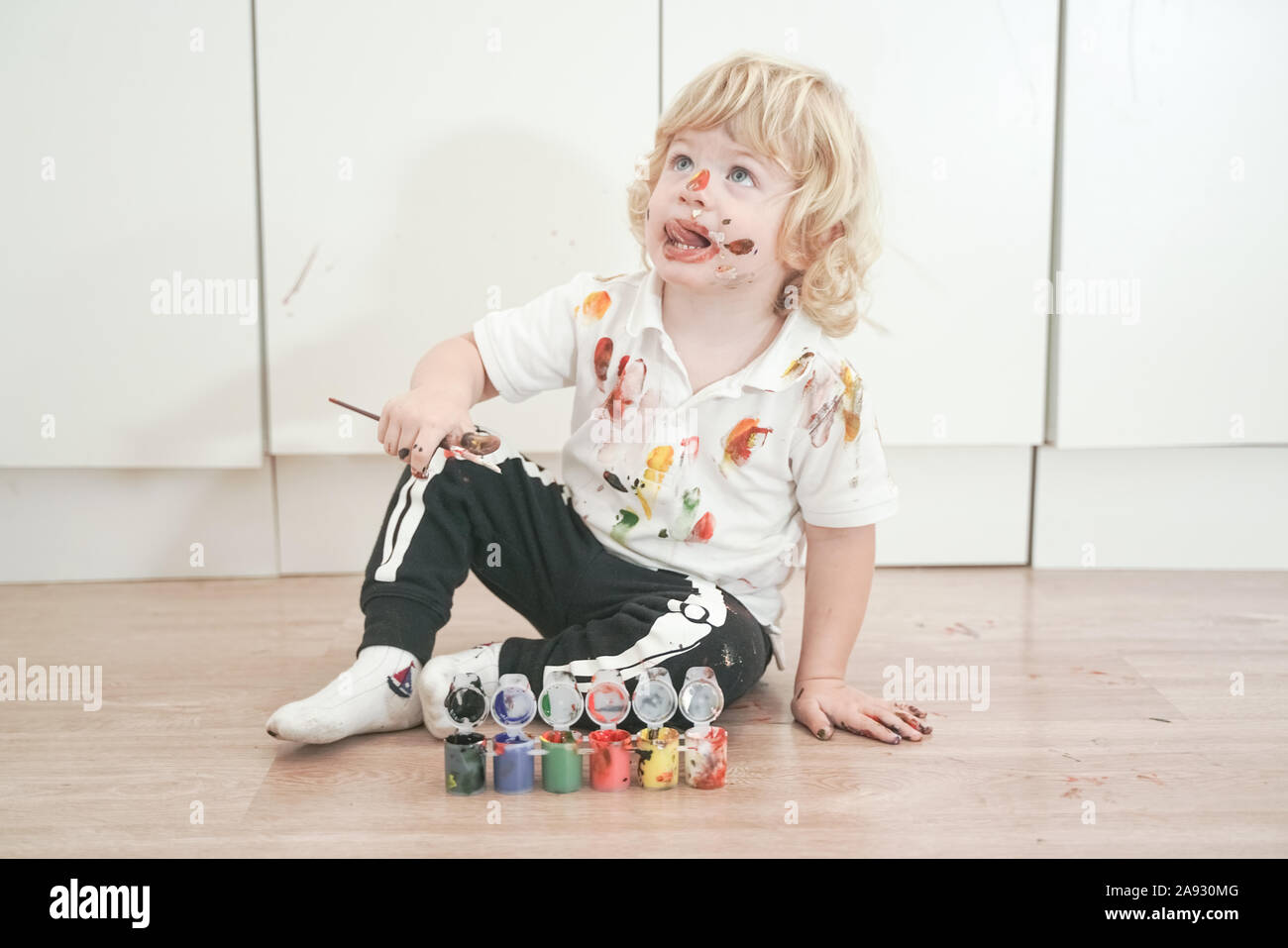 two year old boy with hands and face painted in colorful paints ready ...