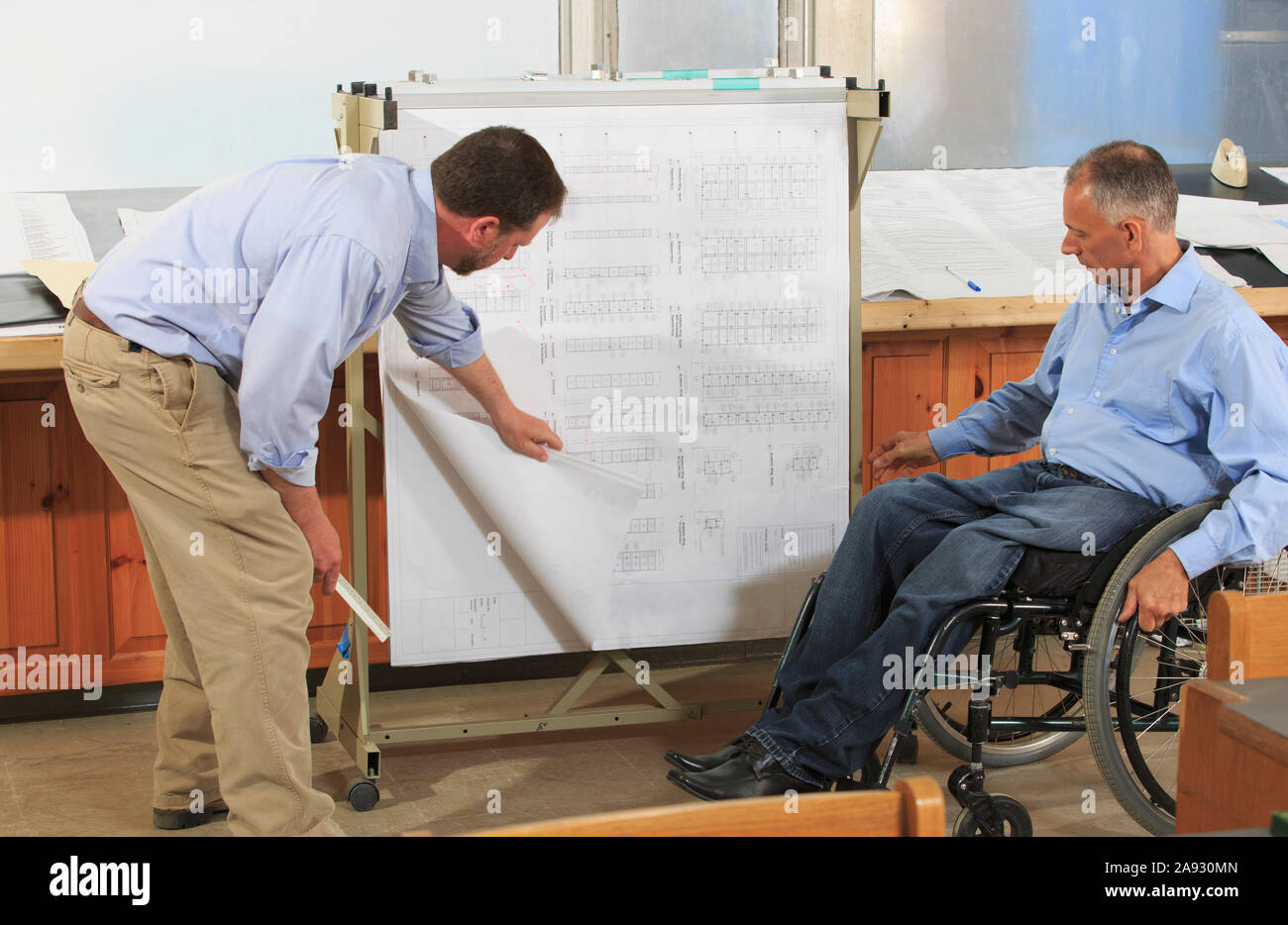 Two project engineers using a hanging rack for job site plans, one in a ...