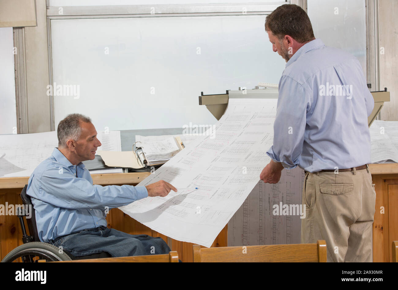 Two project engineers using a hanging rack for job site plans, one in a ...