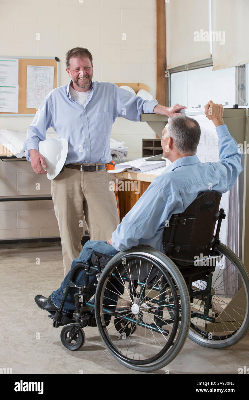 Two project engineers talking about the job, one in a wheelchair with a ...