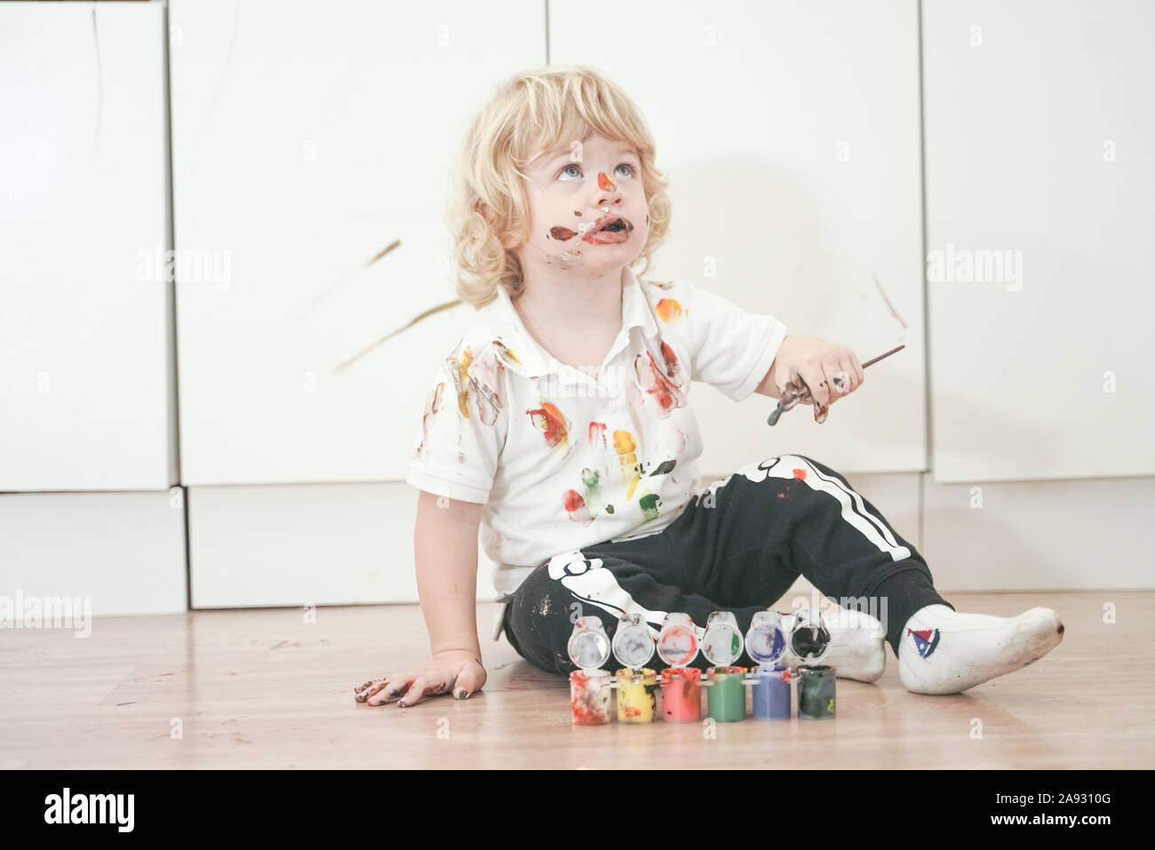 two year old boy with hands and face painted in colorful paints ready ...