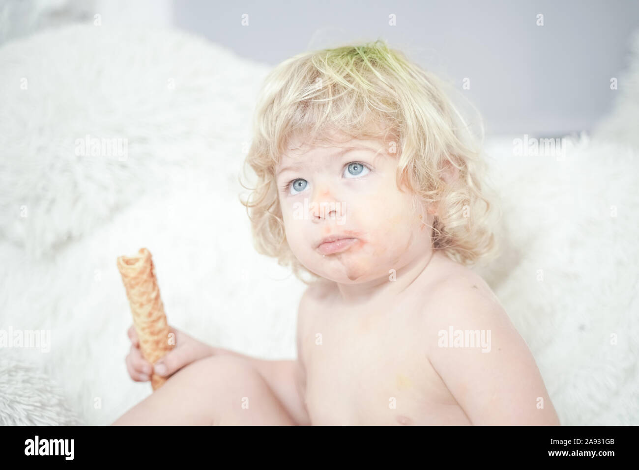 little child taking waffle and eating it with pleasure and fun on white ...