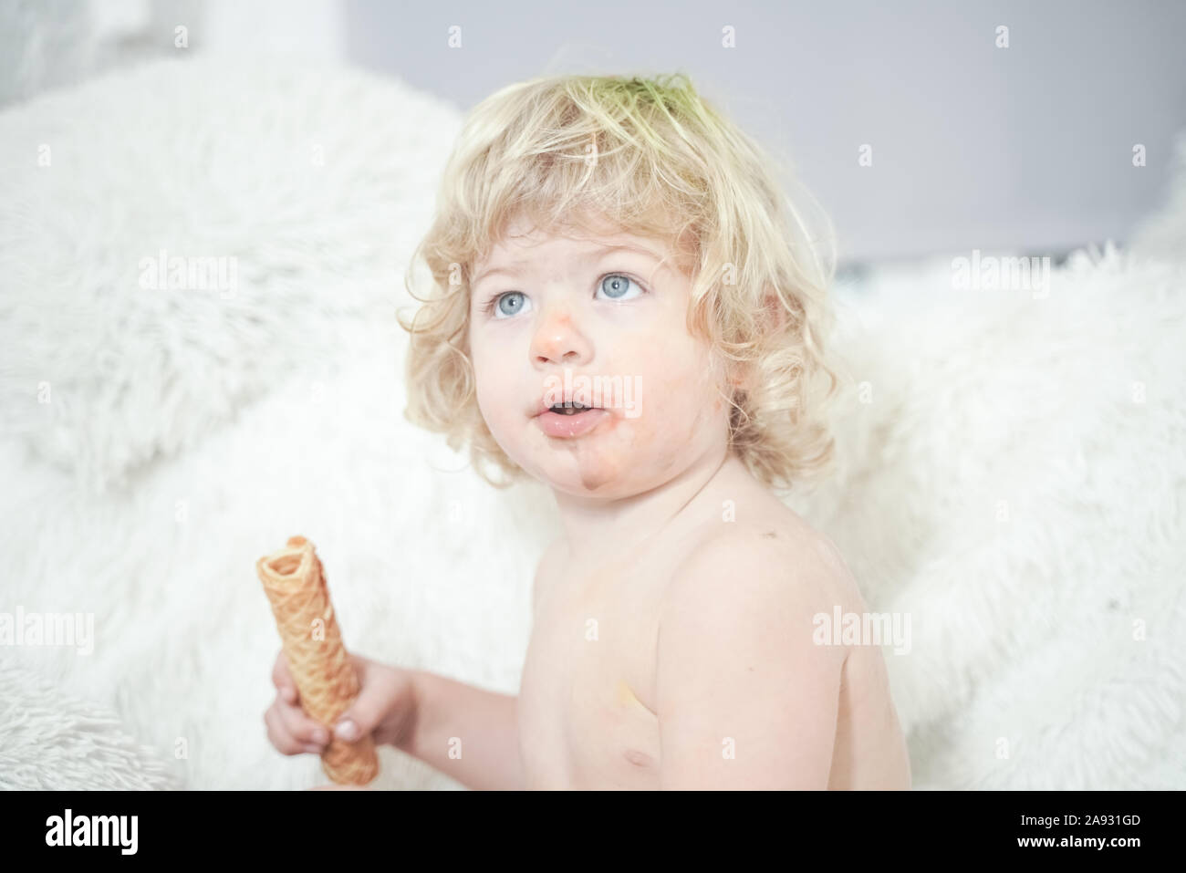 little child taking waffle and eating it with pleasure and fun on white ...
