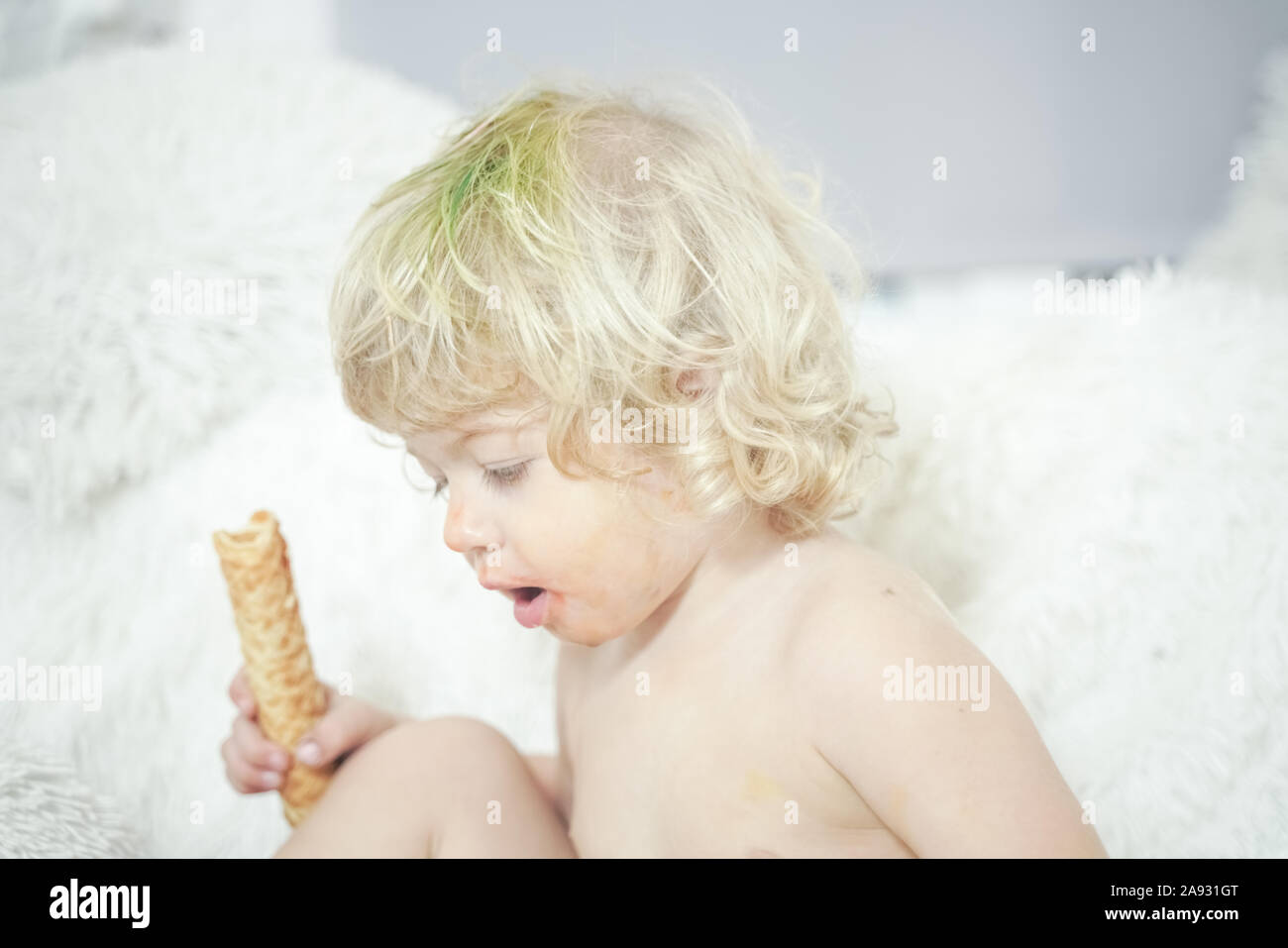 little child taking waffle and eating it with pleasure and fun on white ...