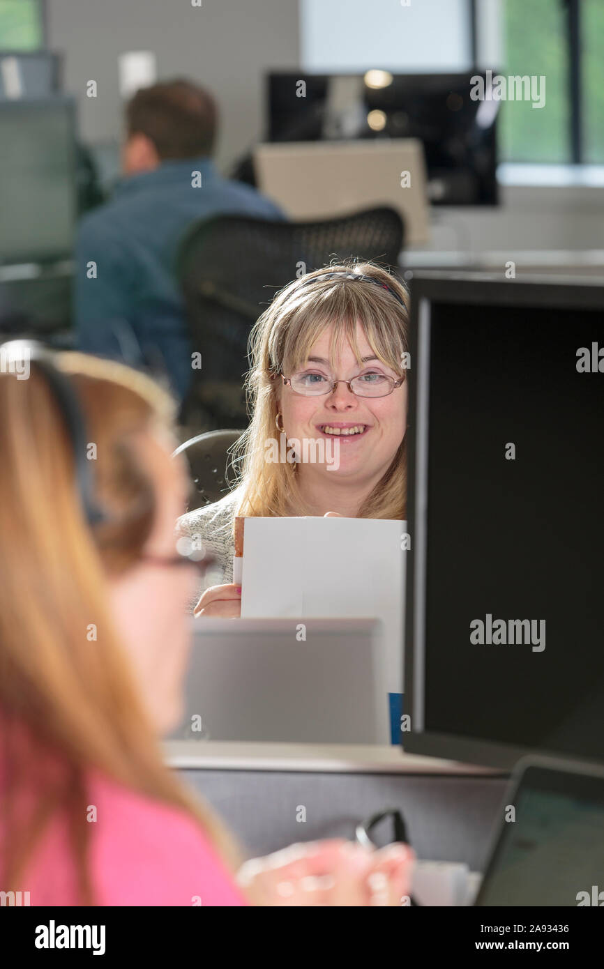 Young woman with Down Syndrome working at her computer in an office ...