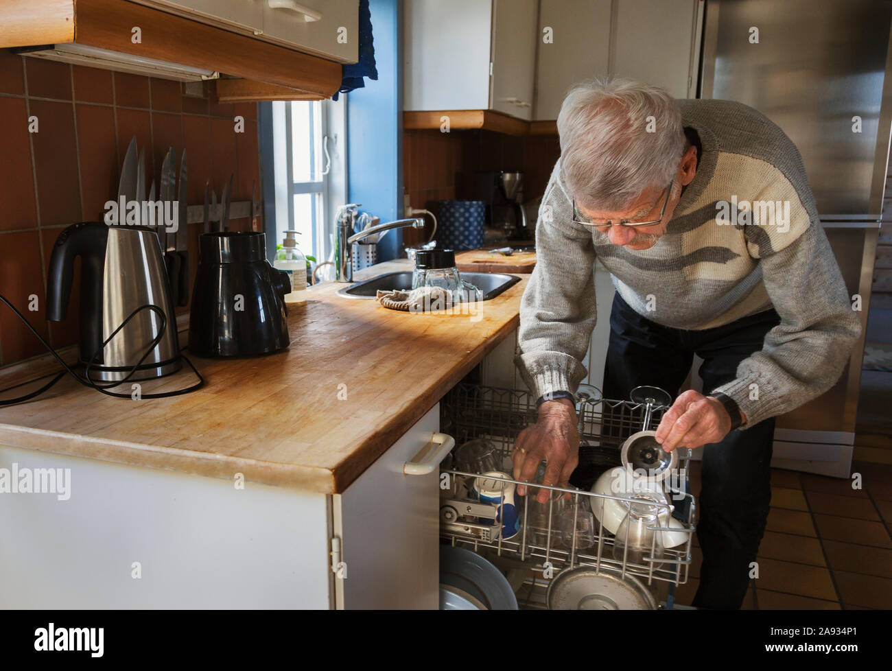 Man putting dishes into dishwasher Stock Photo - Alamy