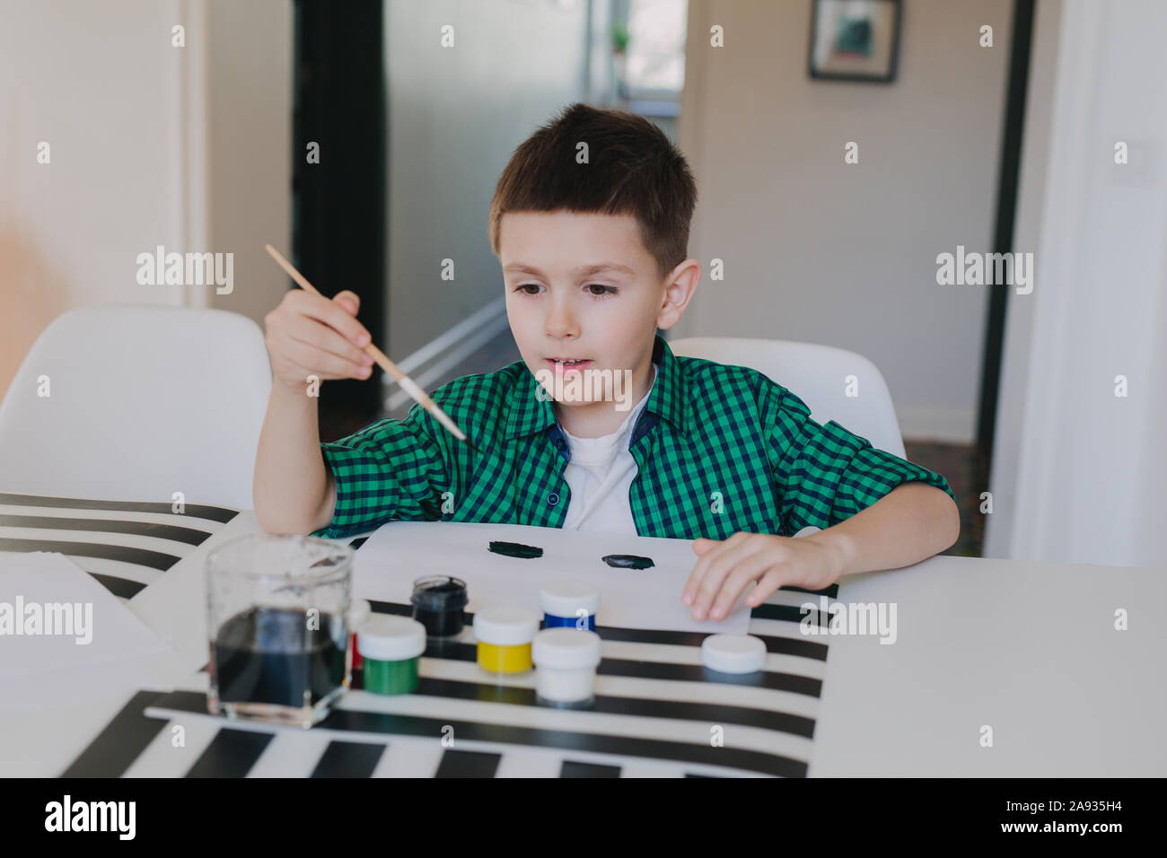 Beautiful little boy having fun painting with water colors at home ...