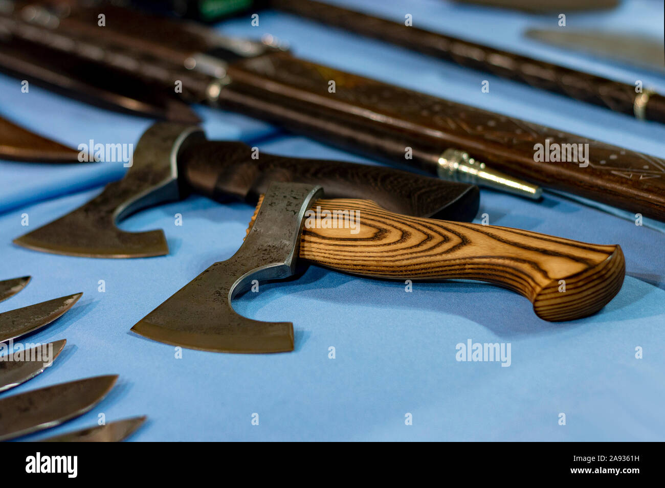 Two small axes with wooden handles on a table among knives and sabers ...