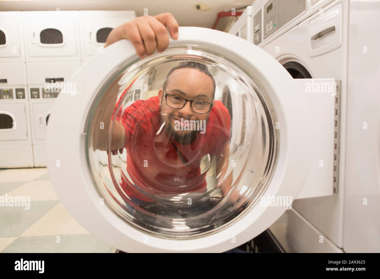 Happy African American man with Down Syndrome doing laundry in utility ...
