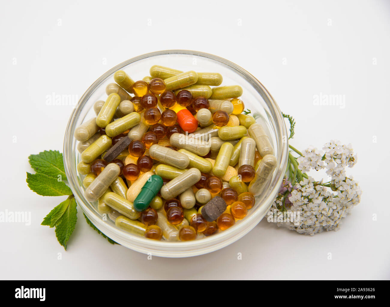 A bowl with various capsules and tablets, medicinal and aromatic herbs ...
