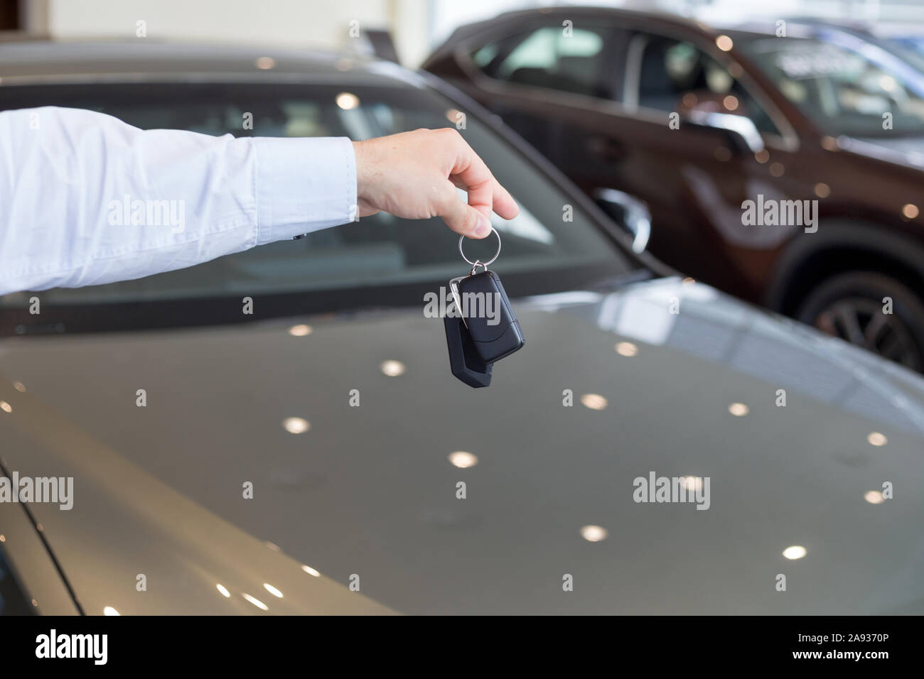 Dealer holding keys to a new car. Modern and prestigious vehicles. For ...