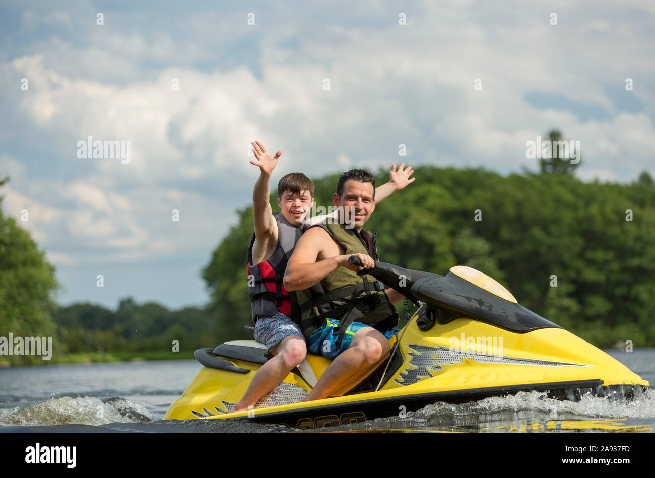 Young man with Down Syndrome riding on a jet ski with his friend in a ...