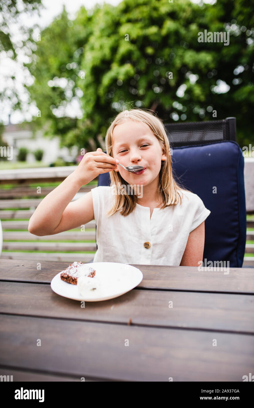 Smiling girl eating cake outside Stock Photo - Alamy