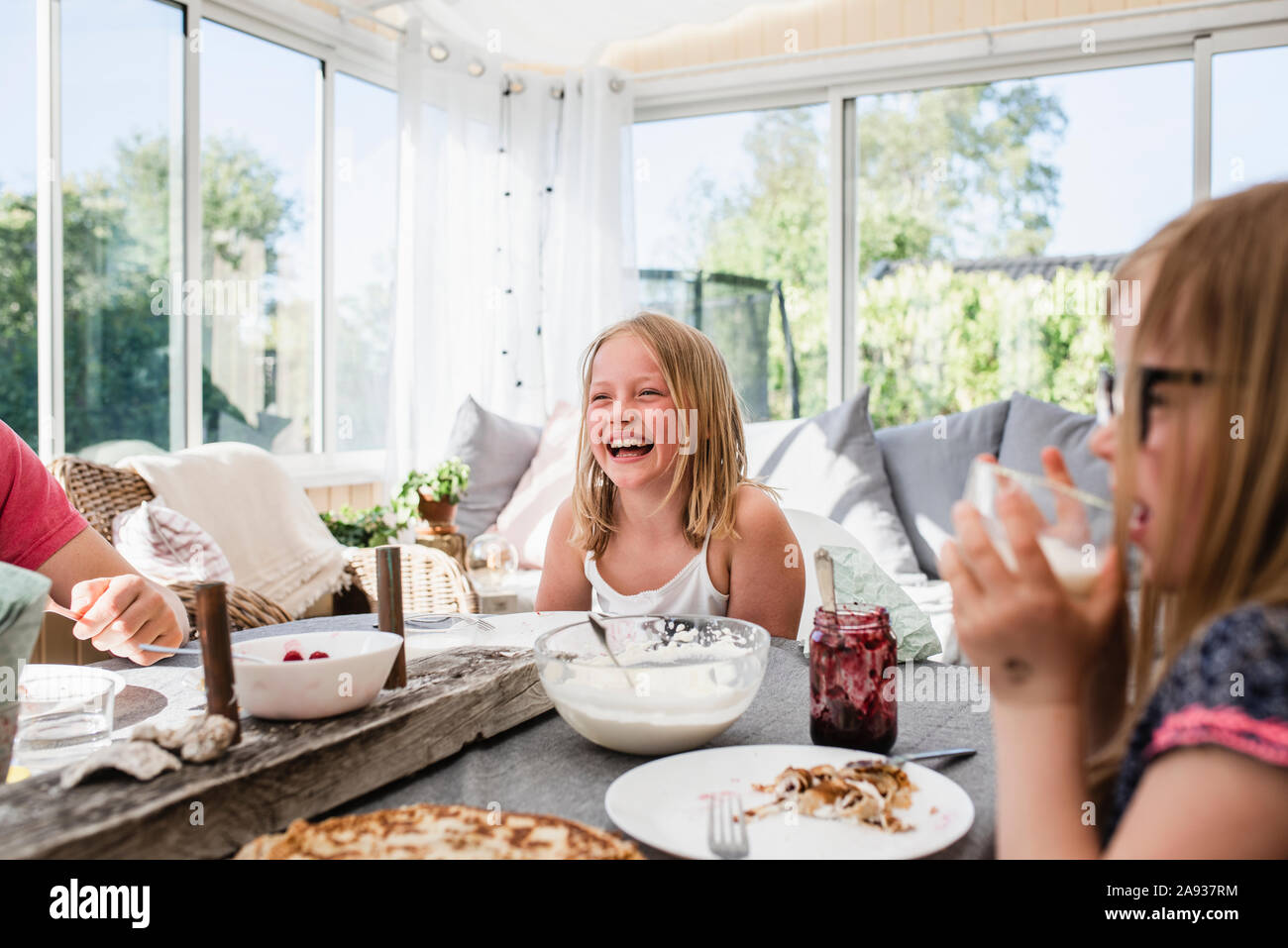 Happy girl at table Stock Photo - Alamy