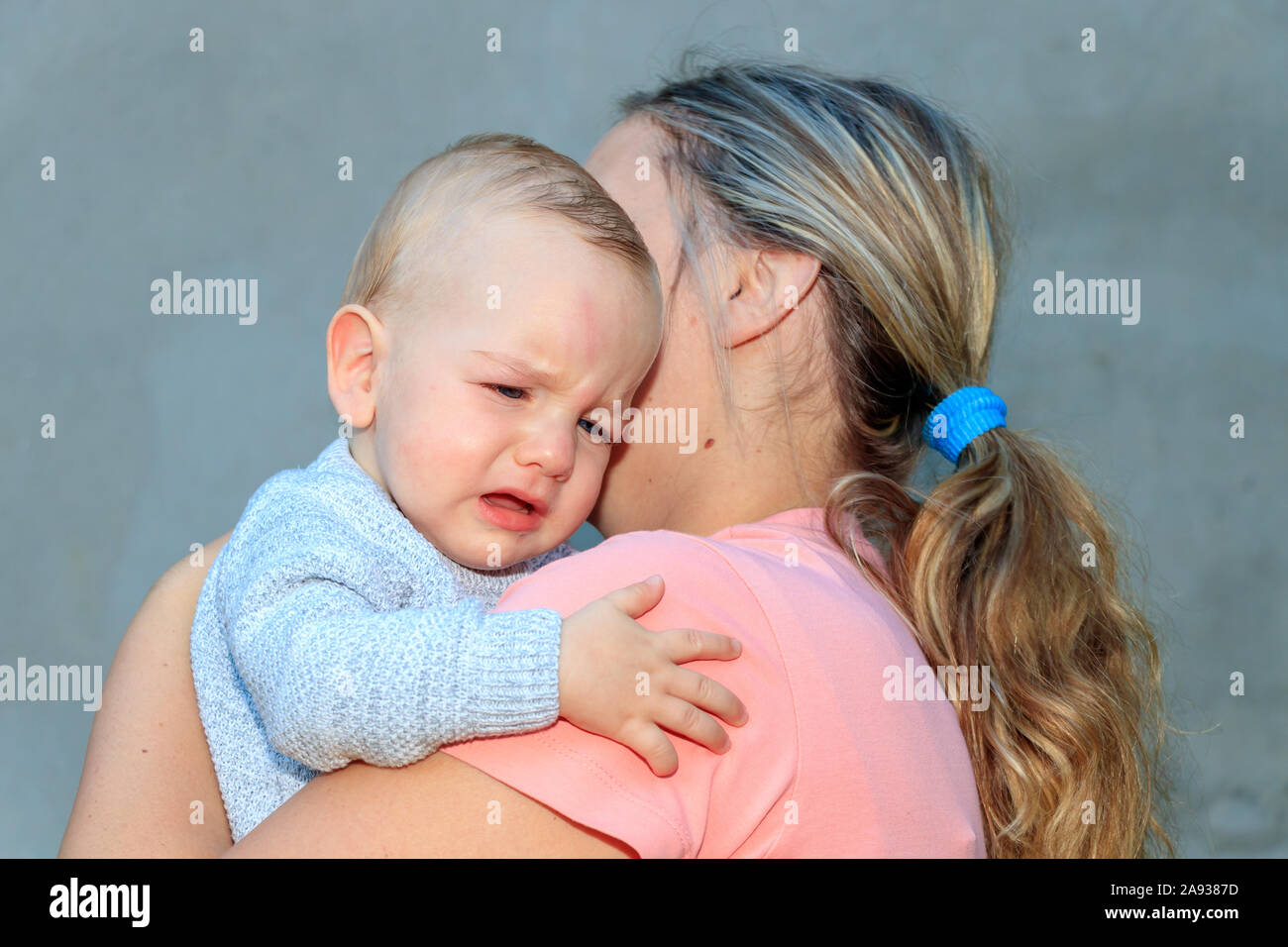 Portrait of a crying baby. The baby boy cries in his mother's embrace ...