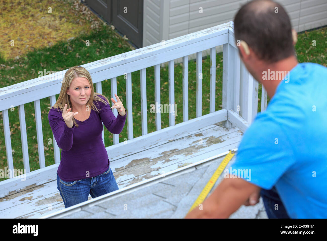 Homeowner signing 'Roof' in American Sign Language to a roofer with ...