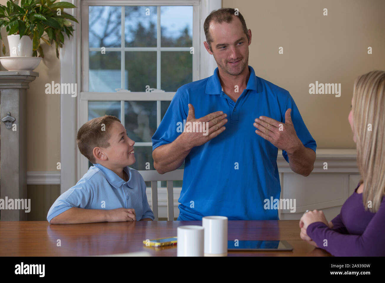 Father saying 'Happy' in American Sign Language to wife and son at home ...