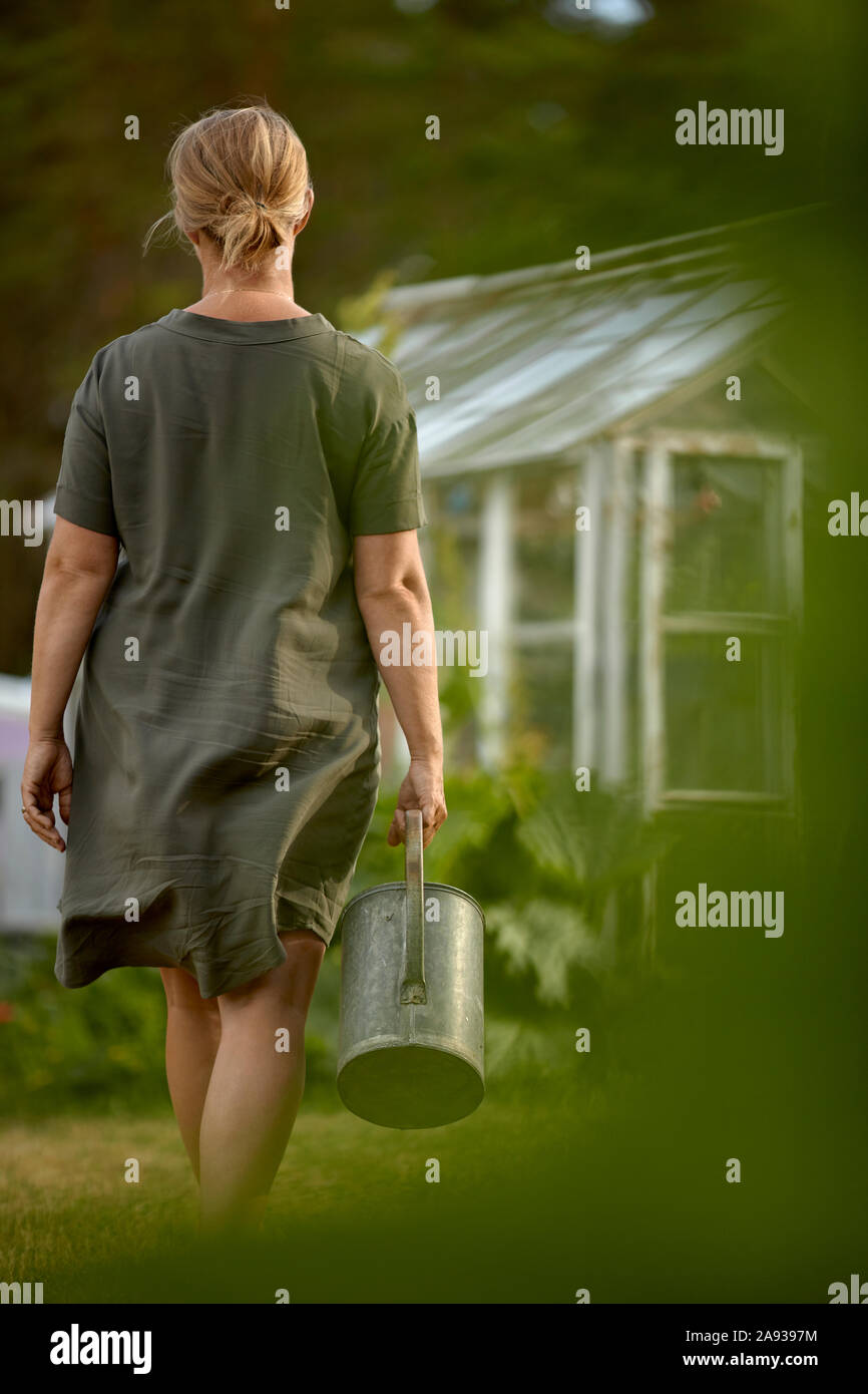 Woman carry watering can Stock Photo - Alamy