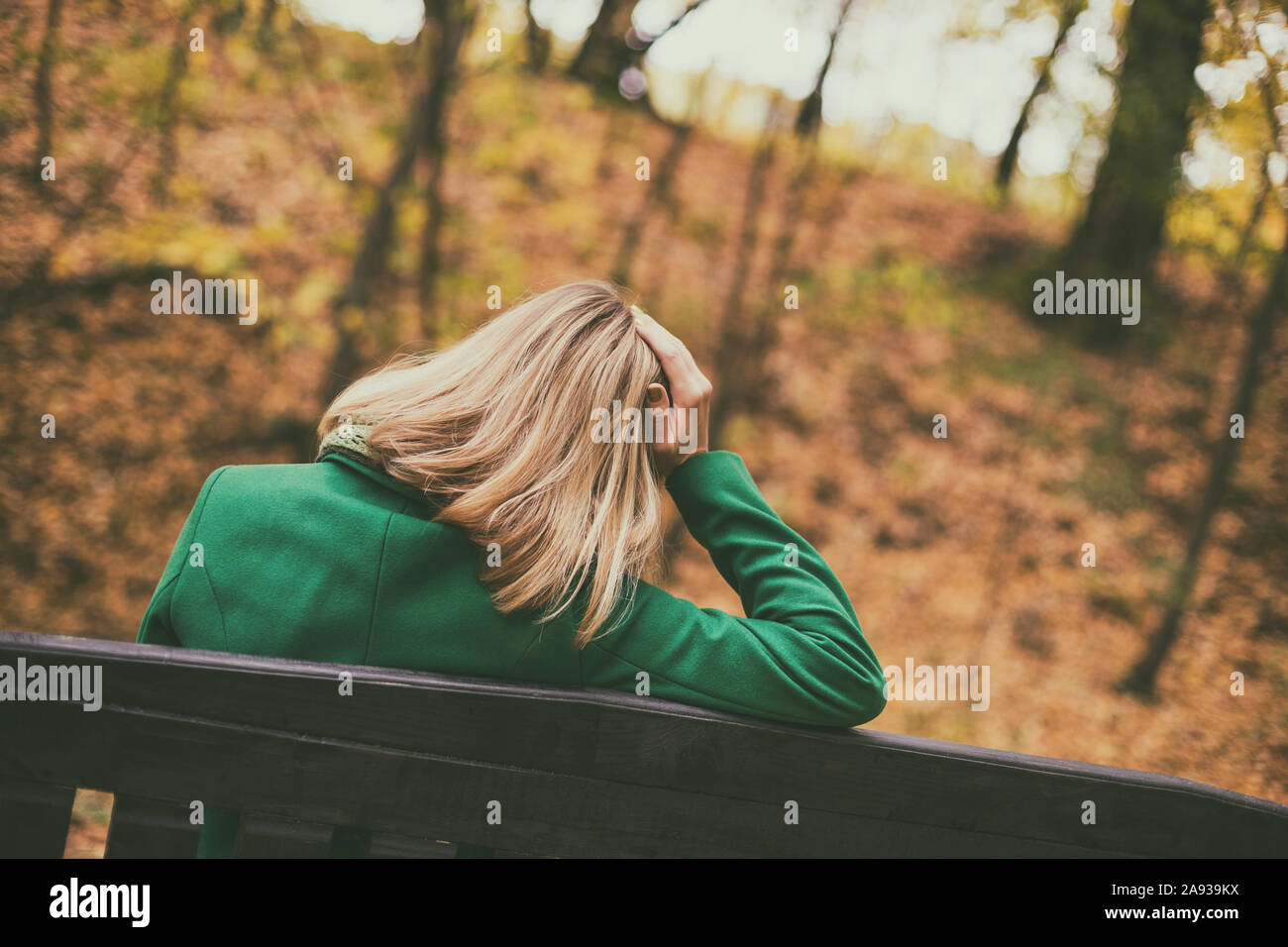 Sad woman sitting on a bench in the park Stock Photo - Alamy