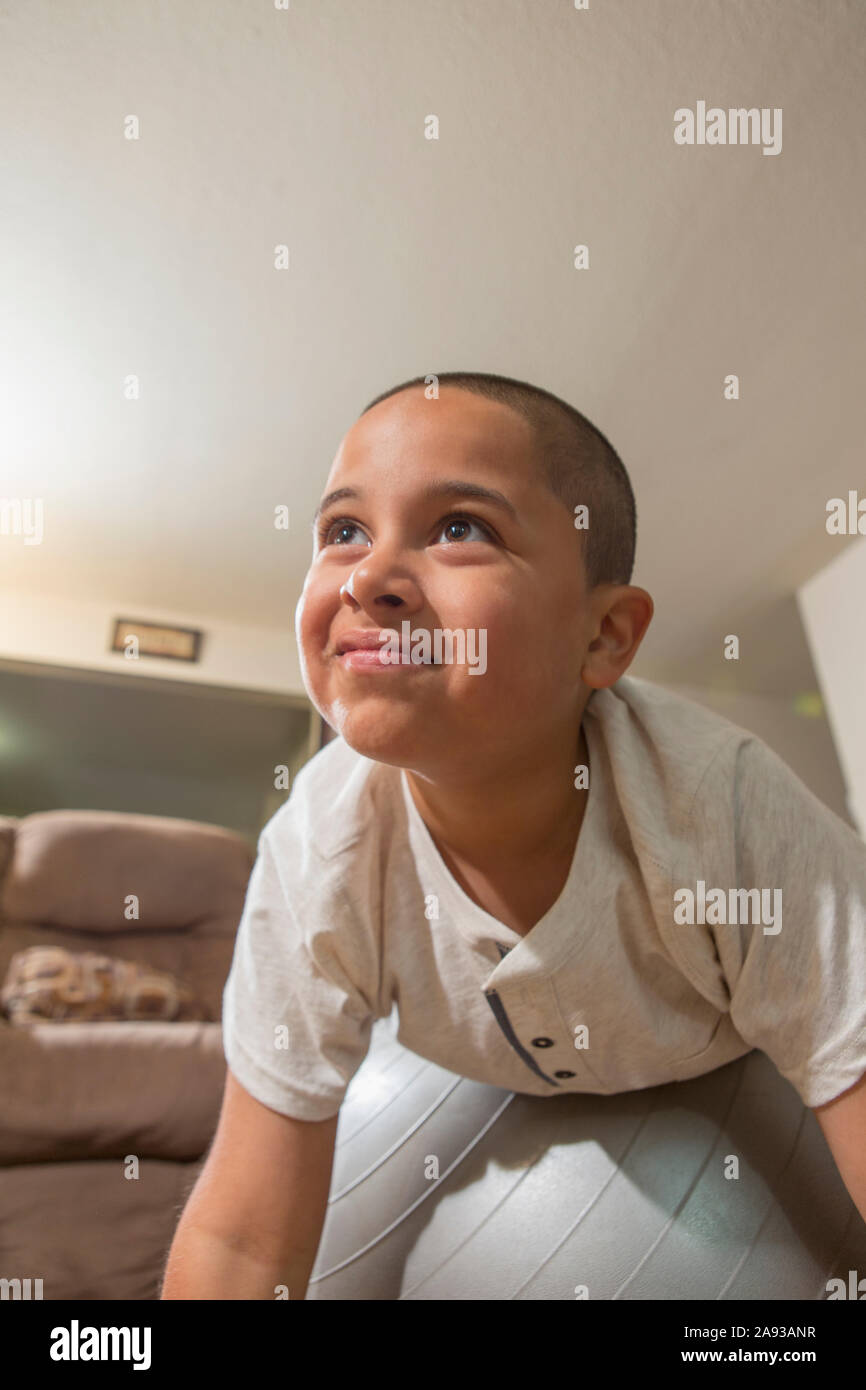 Happy Hispanic boy with Autism playing with an exercise ball in living ...