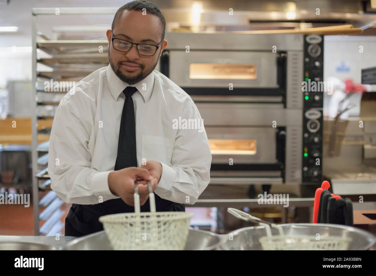 African American man with Down Syndrome as a chef cooking in commercial ...