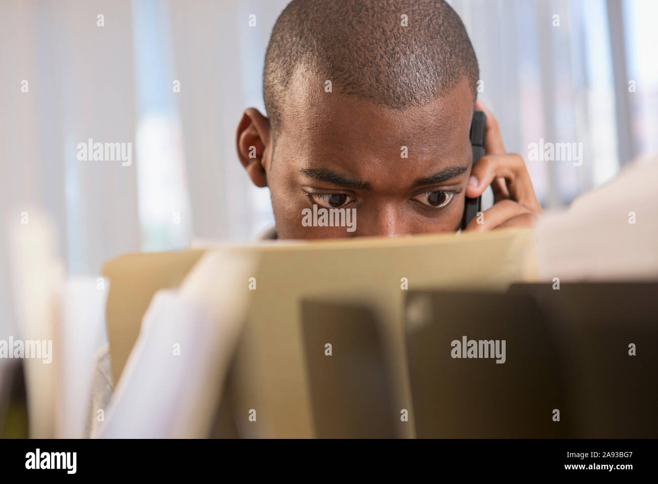 African American man with Autism working in an office staring at papers ...