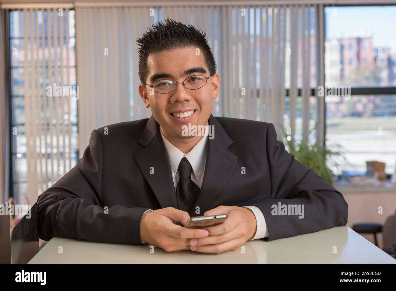Portrait of happy Asian man with Autism using his phone in an office ...