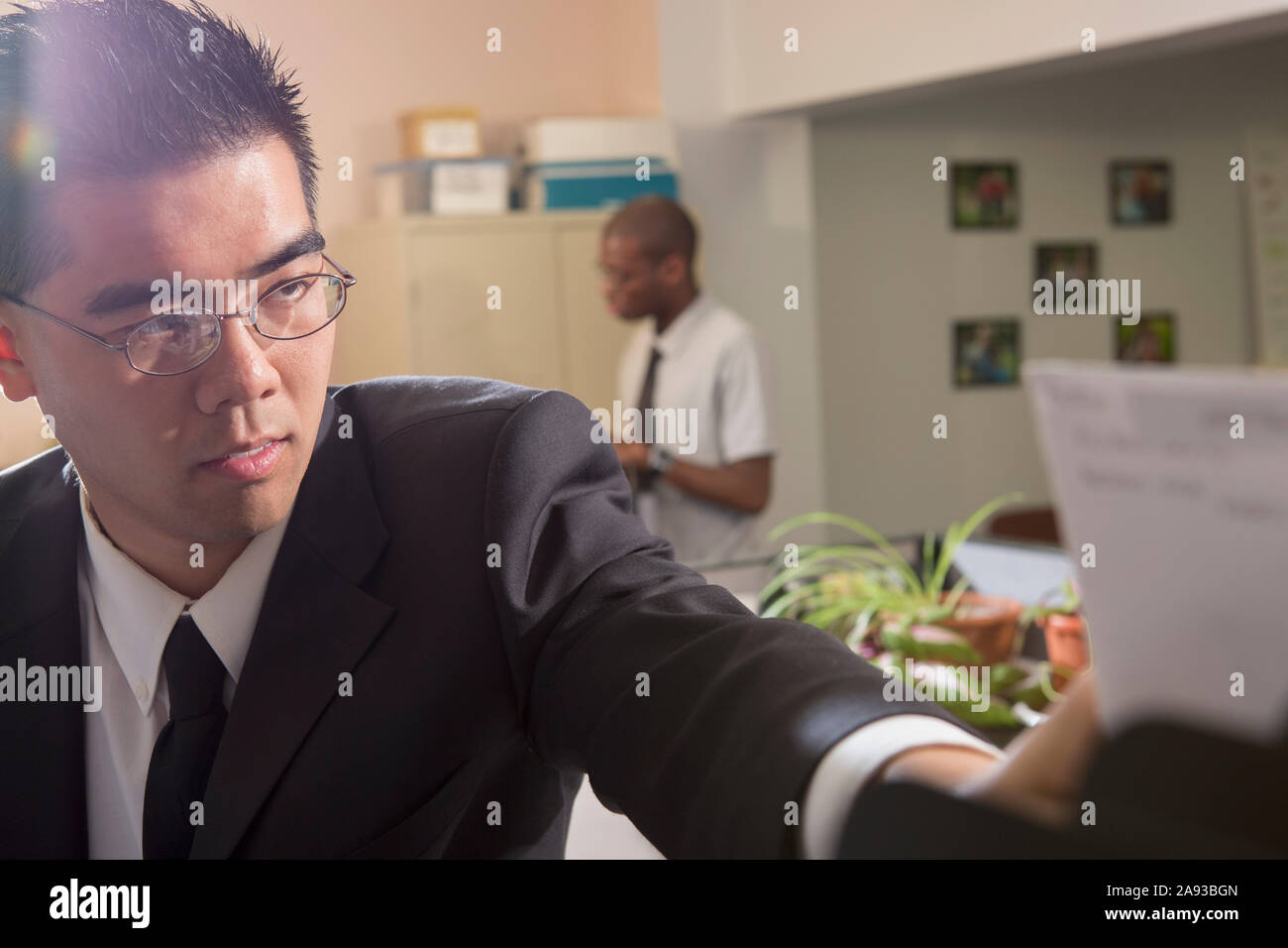 Asian man with Autism working in an office reaching for a paper Stock ...