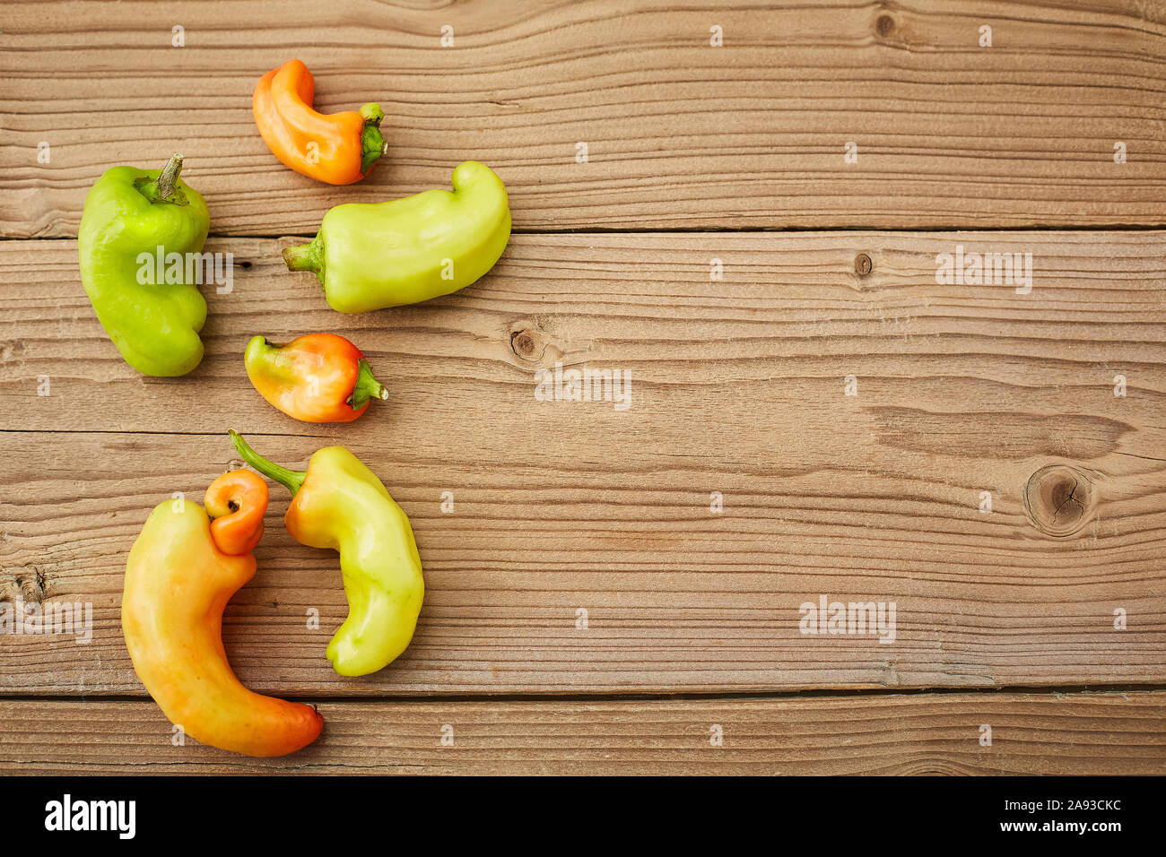 Flat lay Some ugly curved bent chilli peppers on white wooden ...