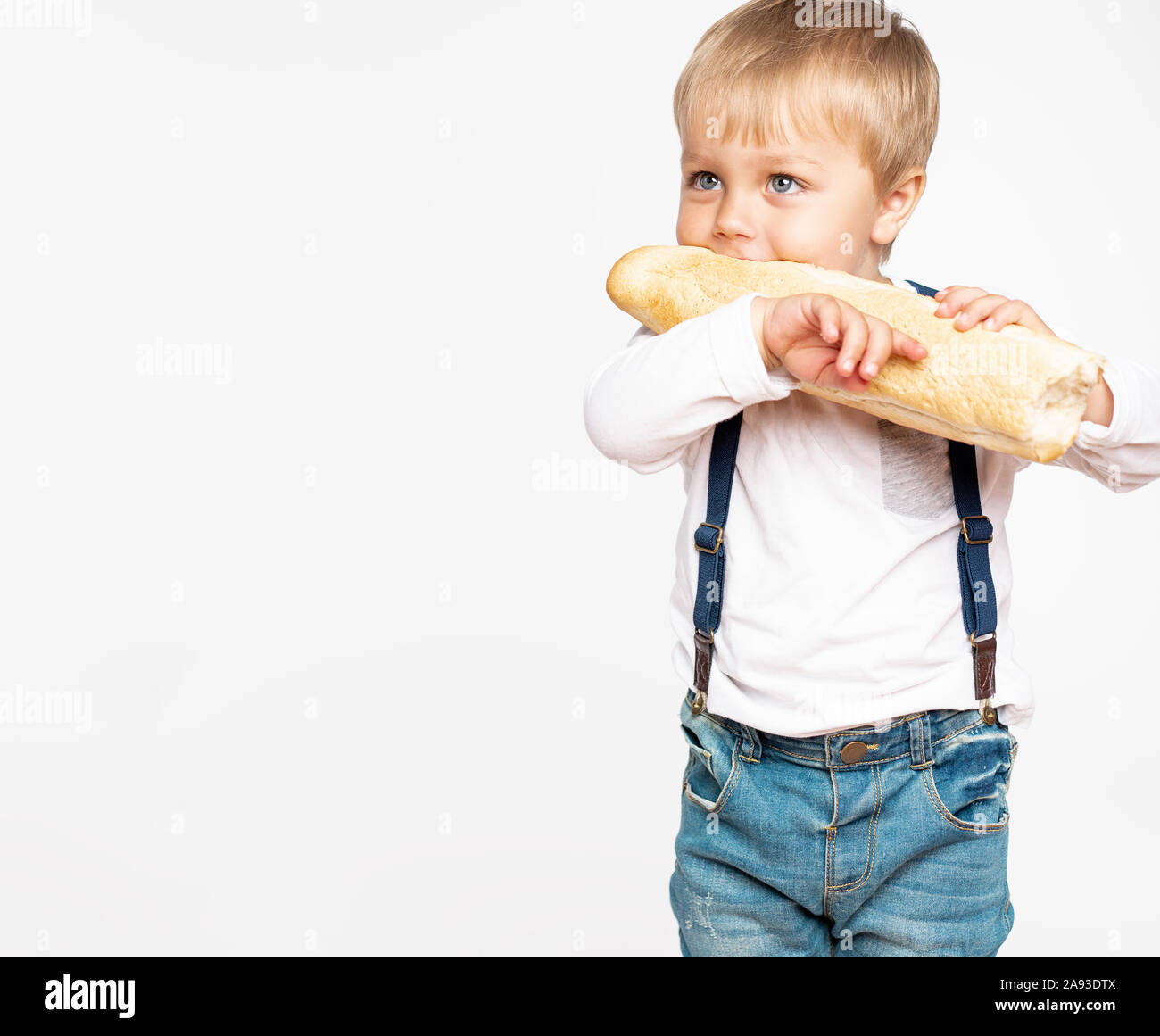 Funny baby boy eating a loaf of bread in studio. Isolated on white ...