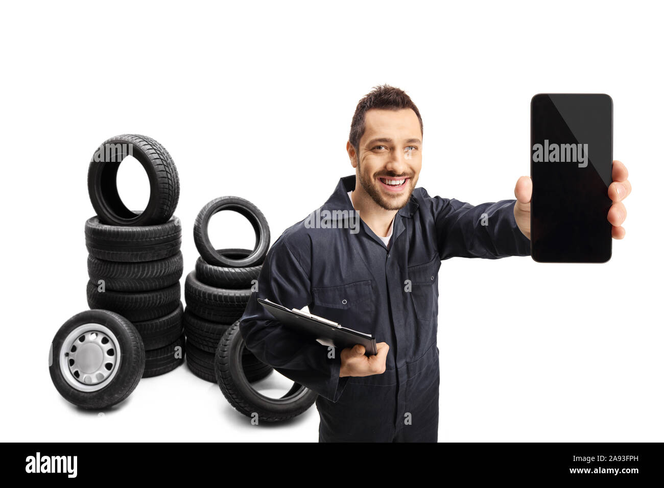 Auto mechanic showing a mobile phone with car tires in the back ...