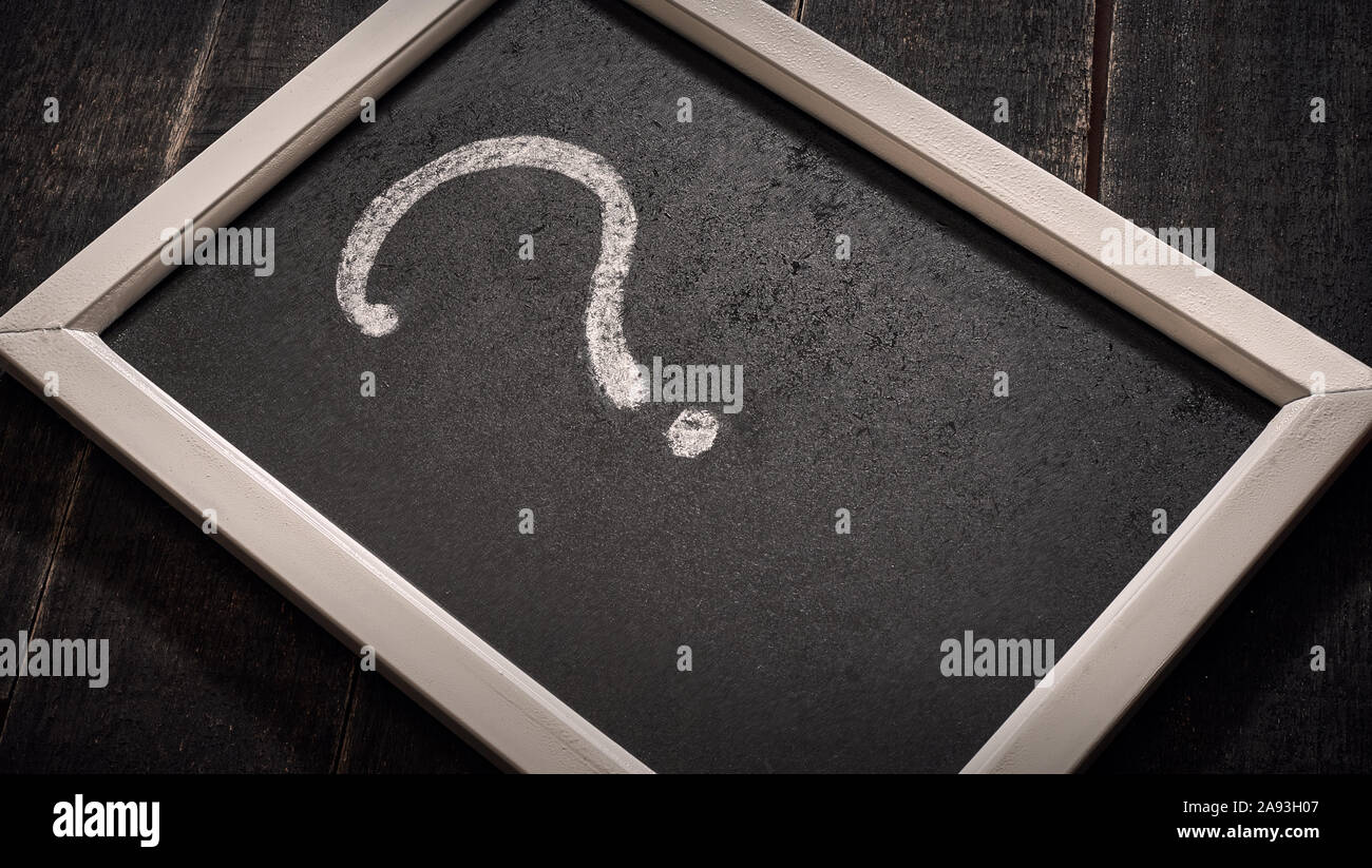 Chalk drawn question mark on a black board on a wooden background. FAQ ...