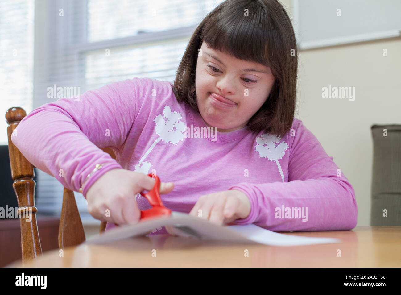 Girl with Down Syndrome cutting a paper with scissors Stock Photo - Alamy