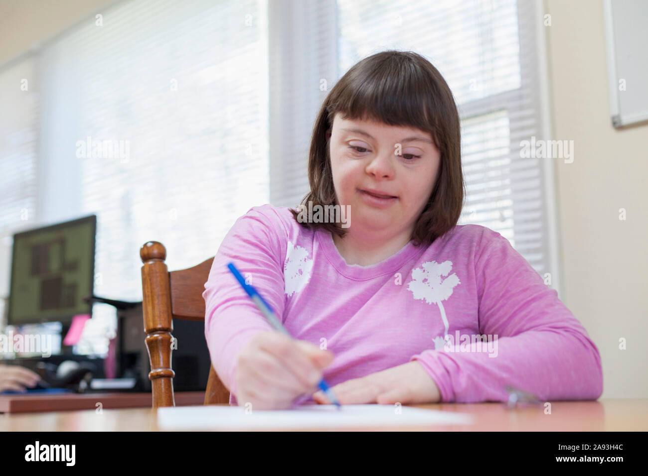 Girl with Down Syndrome writing on a paper Stock Photo - Alamy